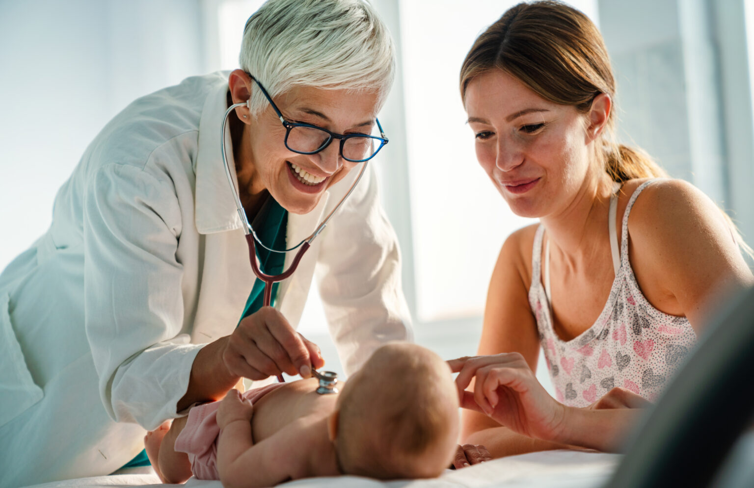 Pediatrician doctor medical examining little smiling baby, held by ...